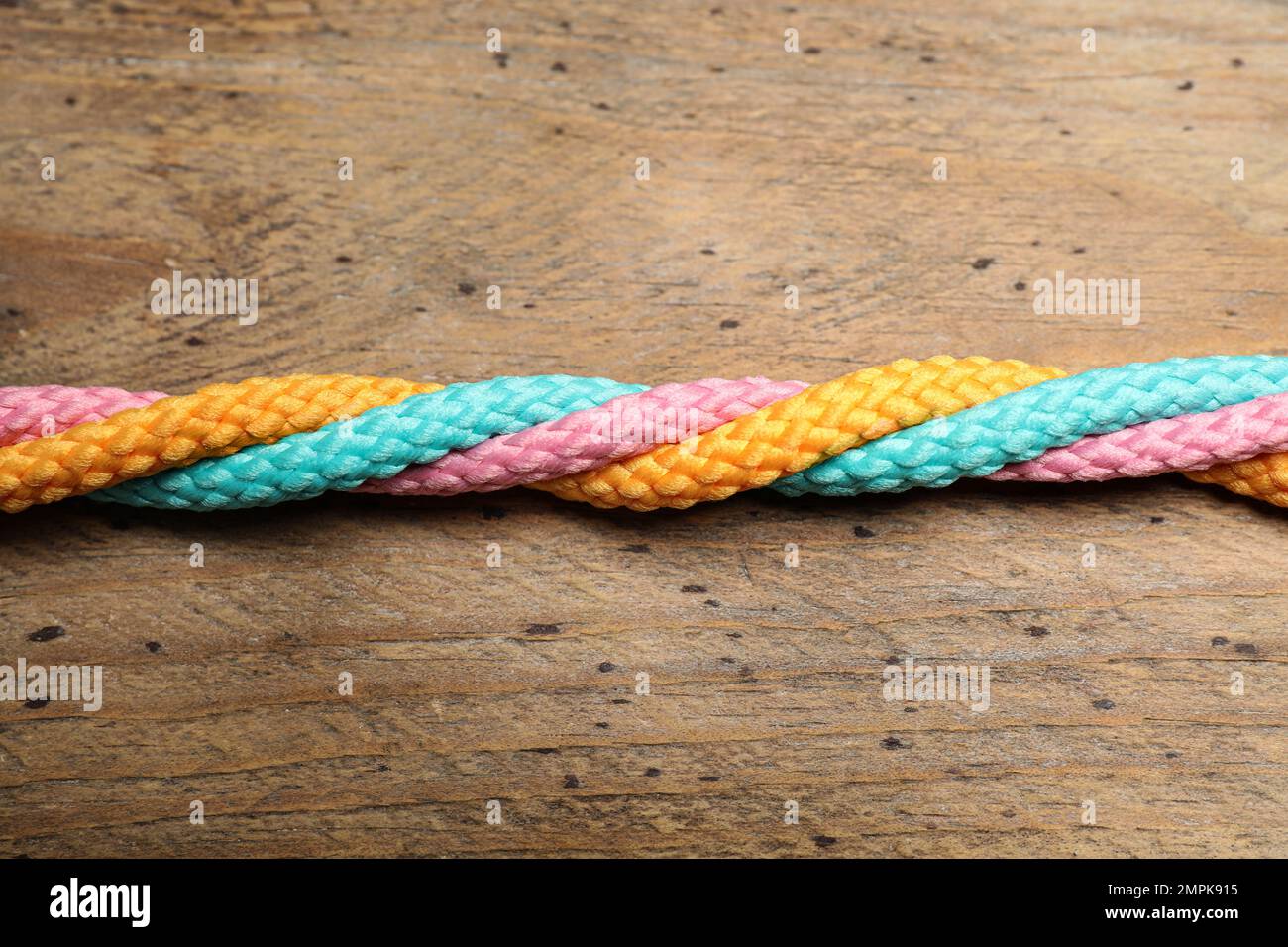 Twisted colorful ropes on wooden background, top view. Unity concept ...