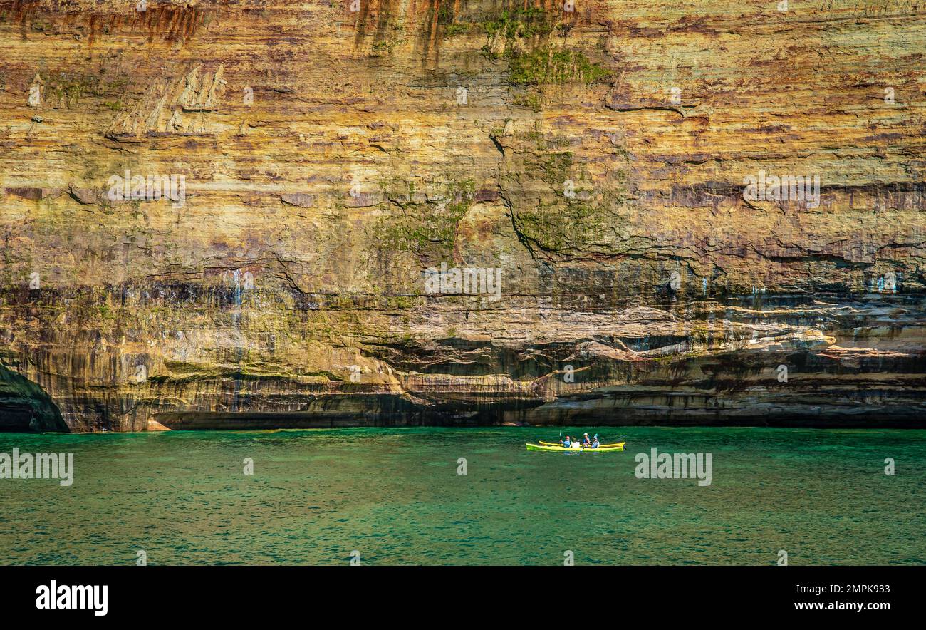 Giant granite rock wall in comparison to tiny kayak in lake northern ...