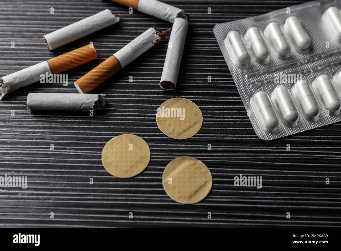 Nicotine patches, pills and broken cigarettes on black table, above ...