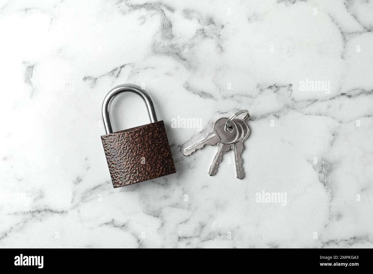 Steel padlock and keys on white marble background, top view. Safety ...