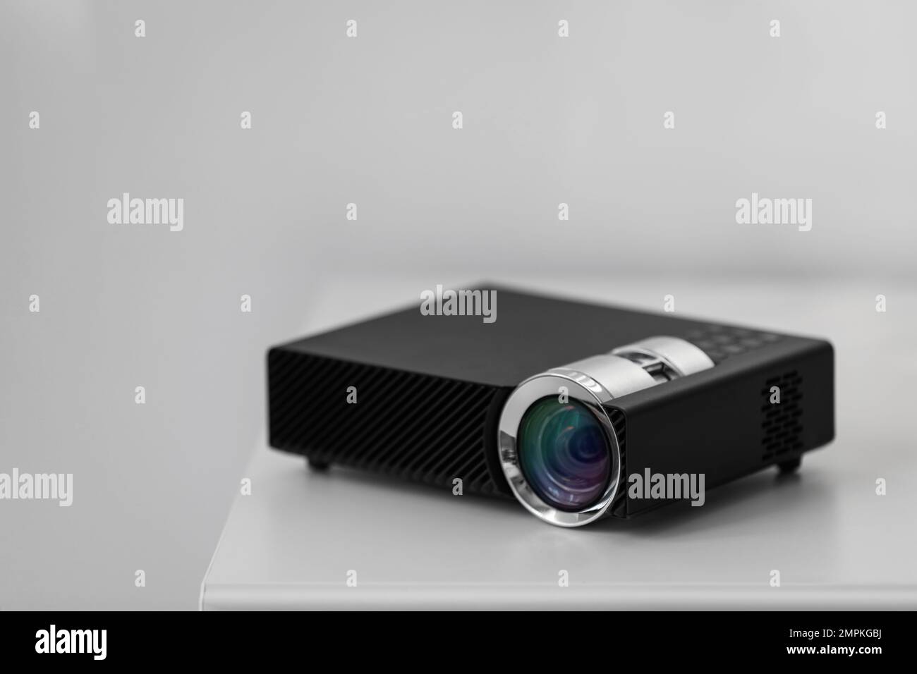 Modern video projector on white table indoors Stock Photo - Alamy