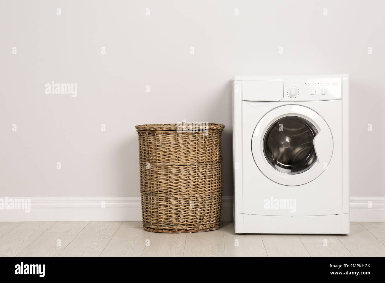 Modern washing machine with laundry basket near white wall Stock Photo ...