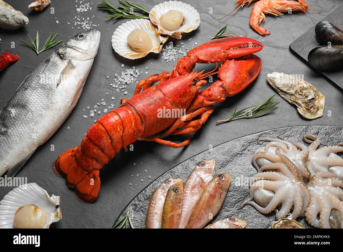 Fresh fish and different seafood on black table Stock Photo - Alamy