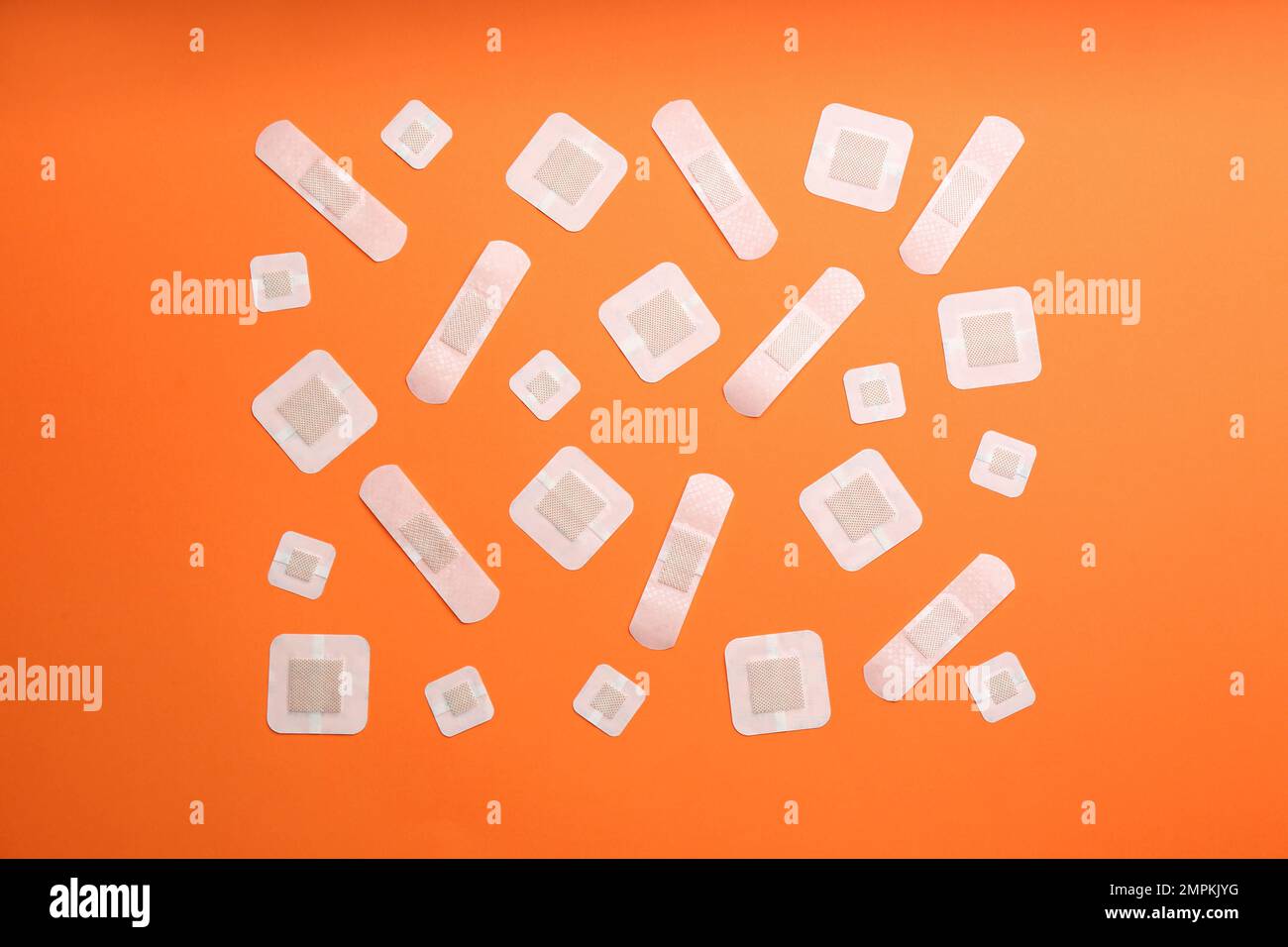 Different types of sticking plasters on orange background, flat lay ...