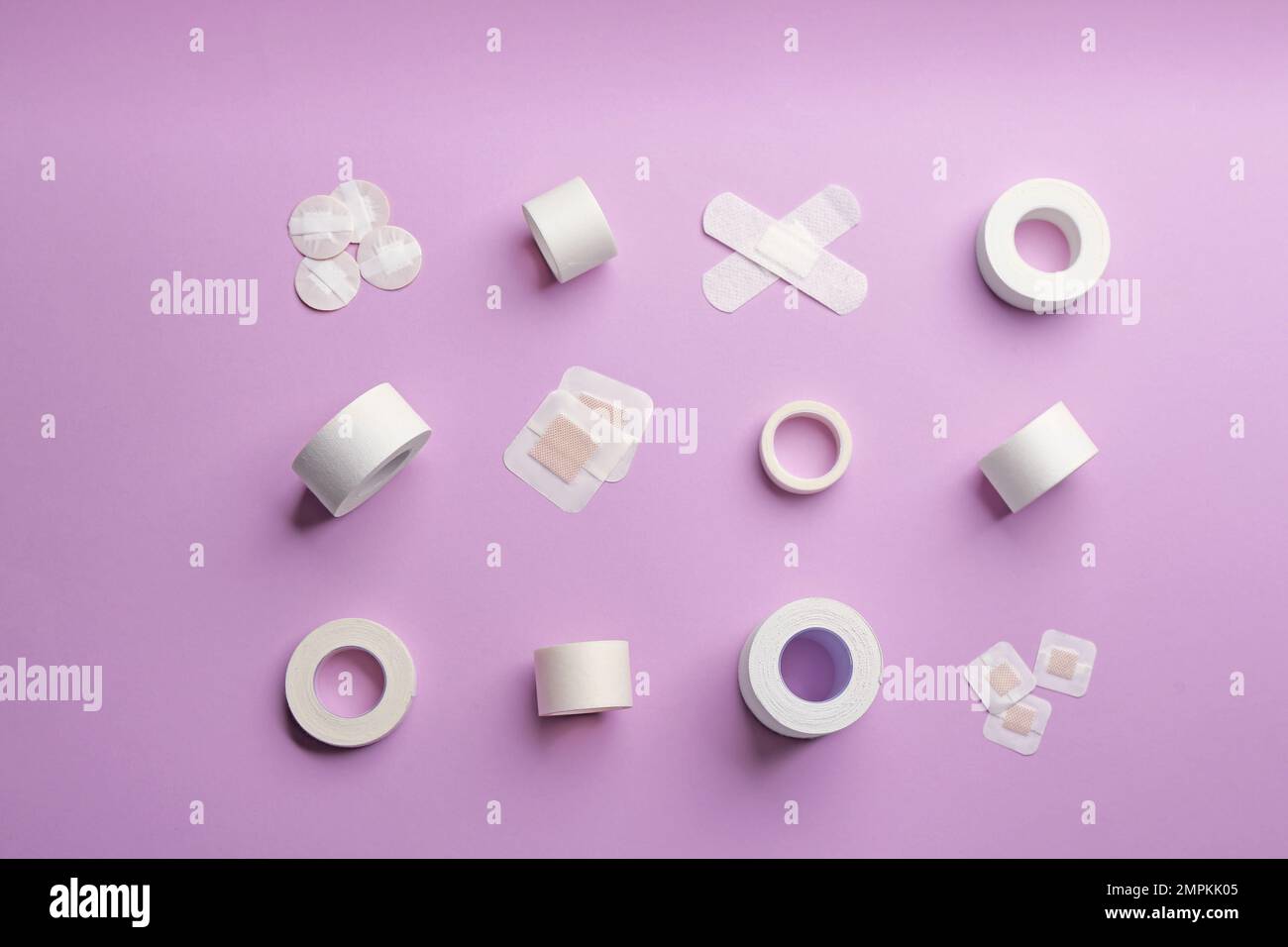 Different types of sticking plasters on lilac background, flat lay ...