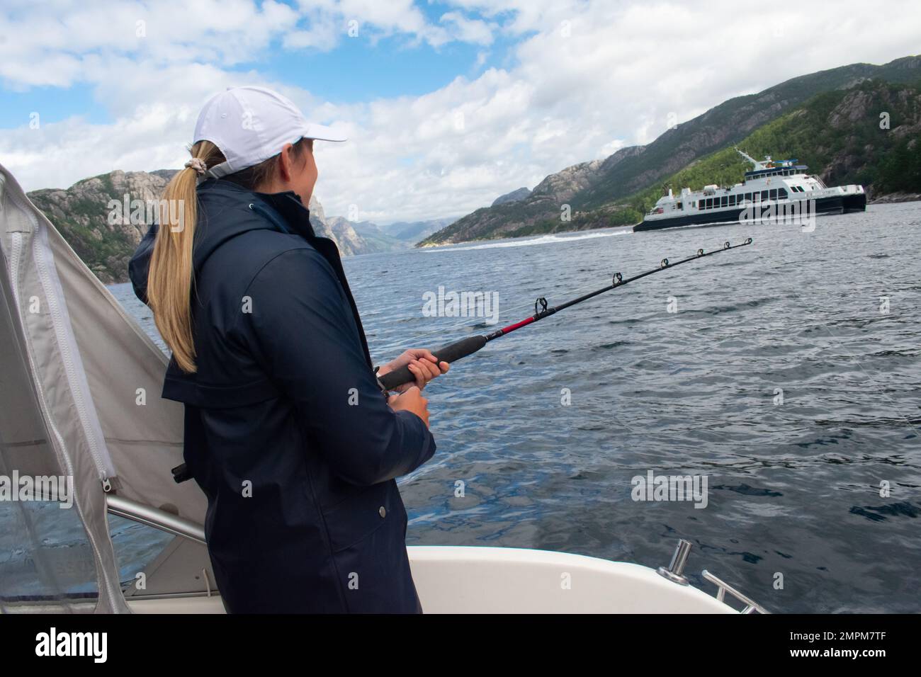 Female Fishing offshore on a boat with fishing rod and reel with ...