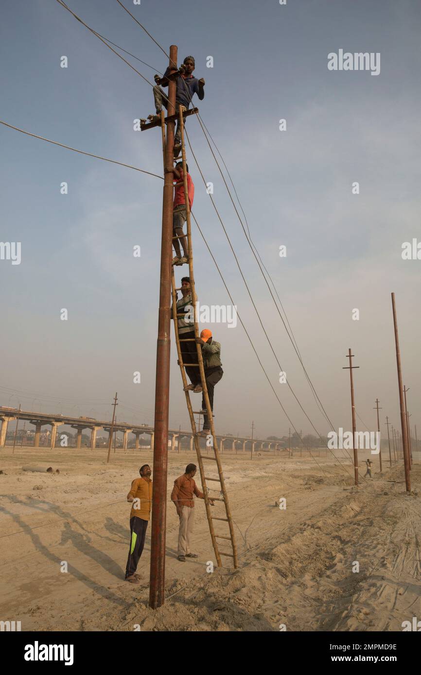 Indian linemen fix a new high tension electric power line on the banks ...