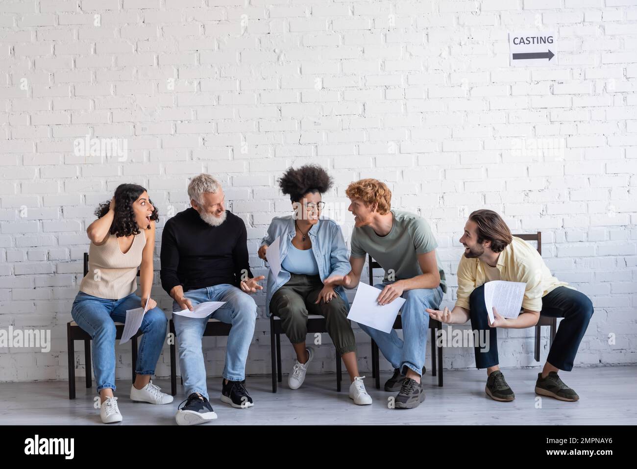 excited multiracial actors with scenarios talking while sitting in ...