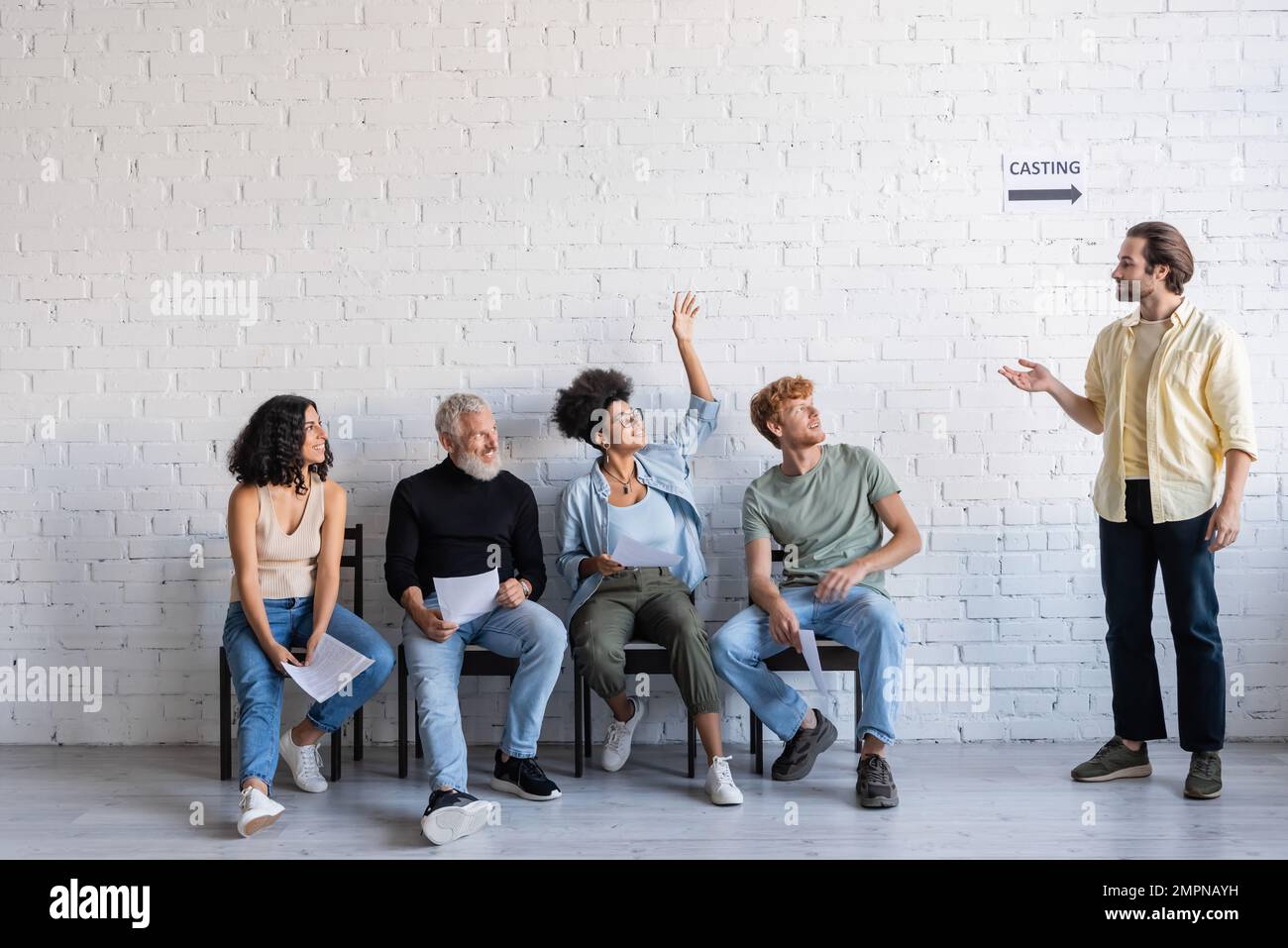 art director pointing at african american woman raising hand near ...