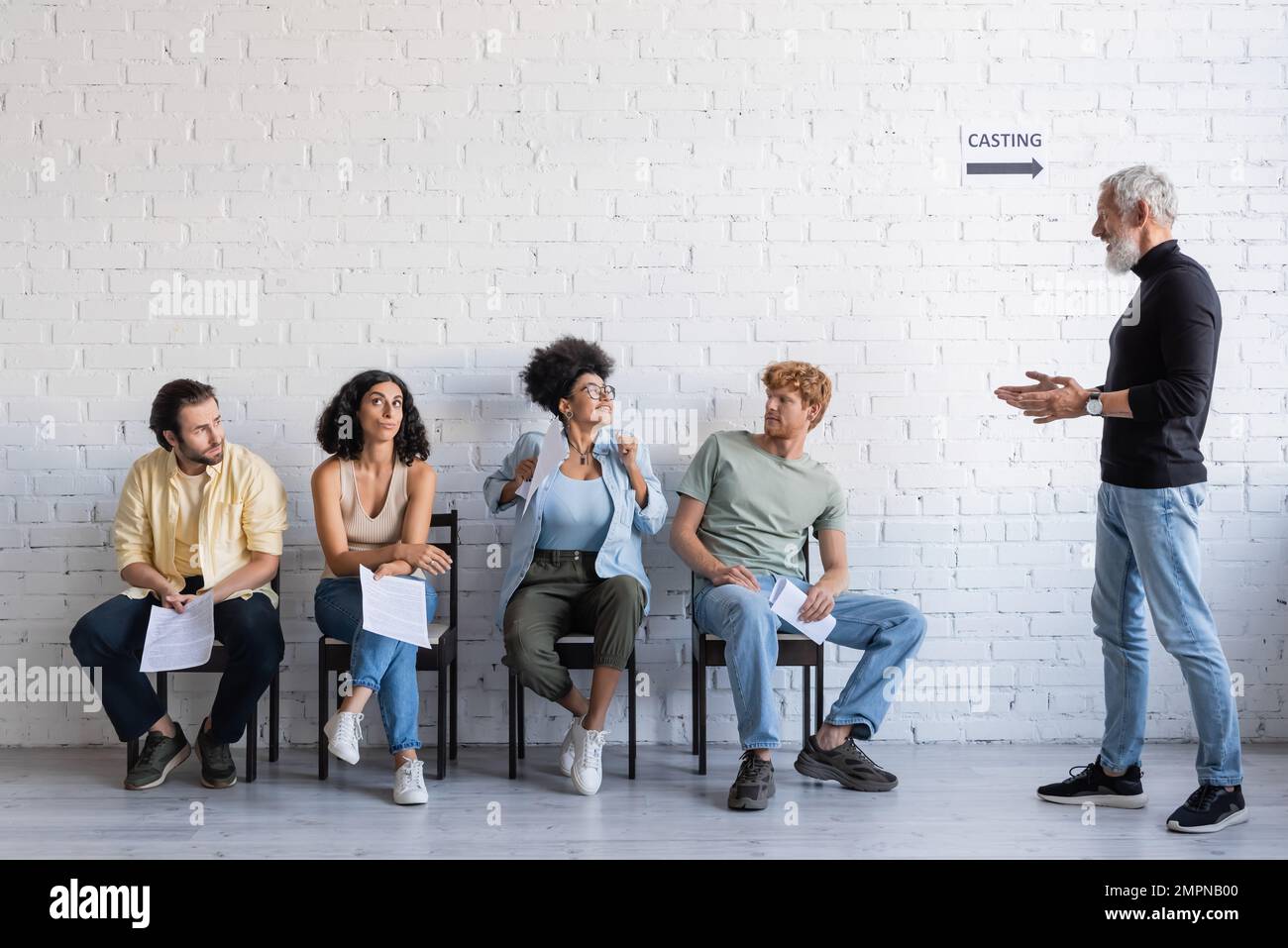 grey haired producer talking to happy african american woman near ...