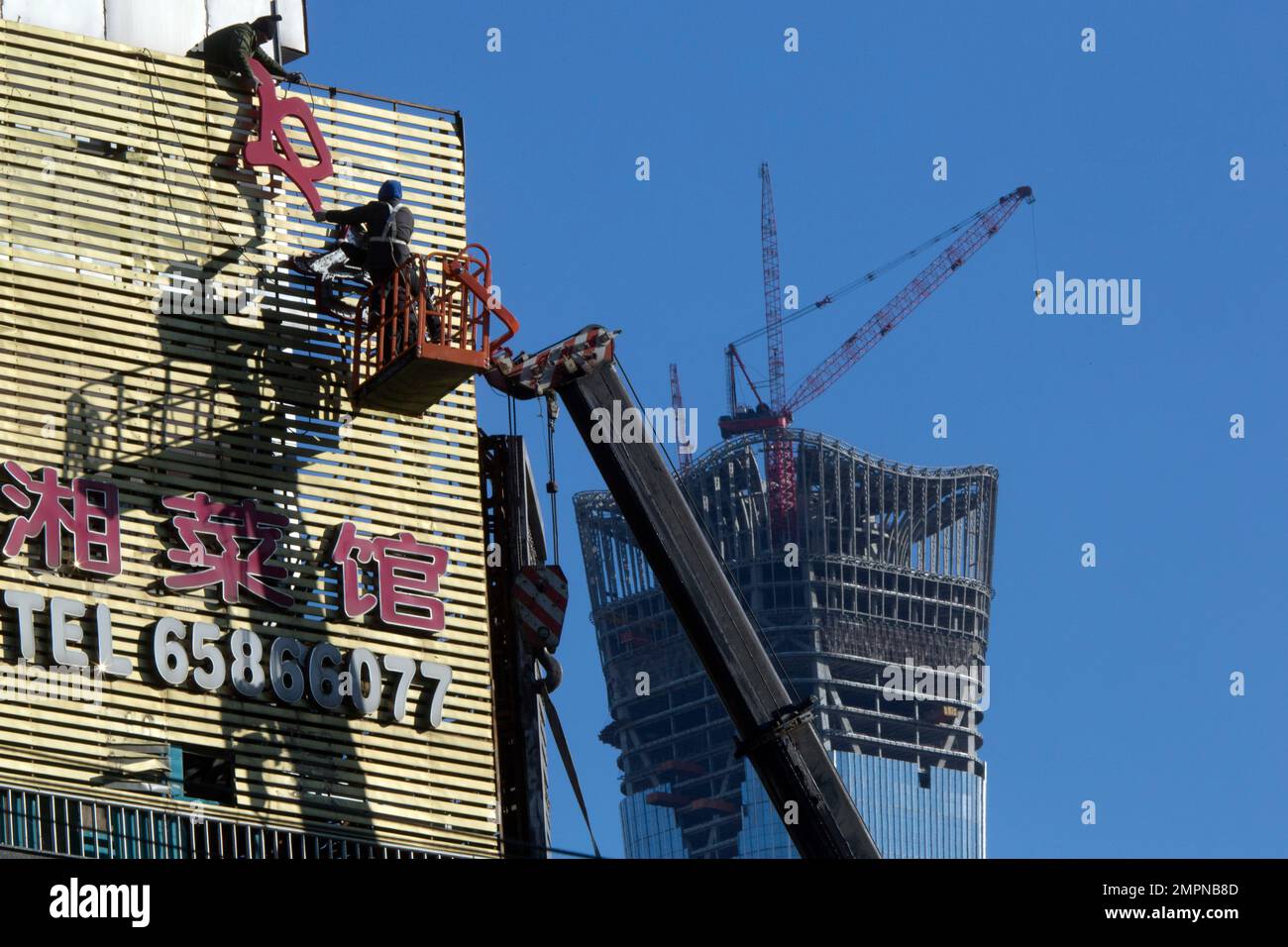 Workers dismantle a signage near the China Zun Tower, the capital's ...
