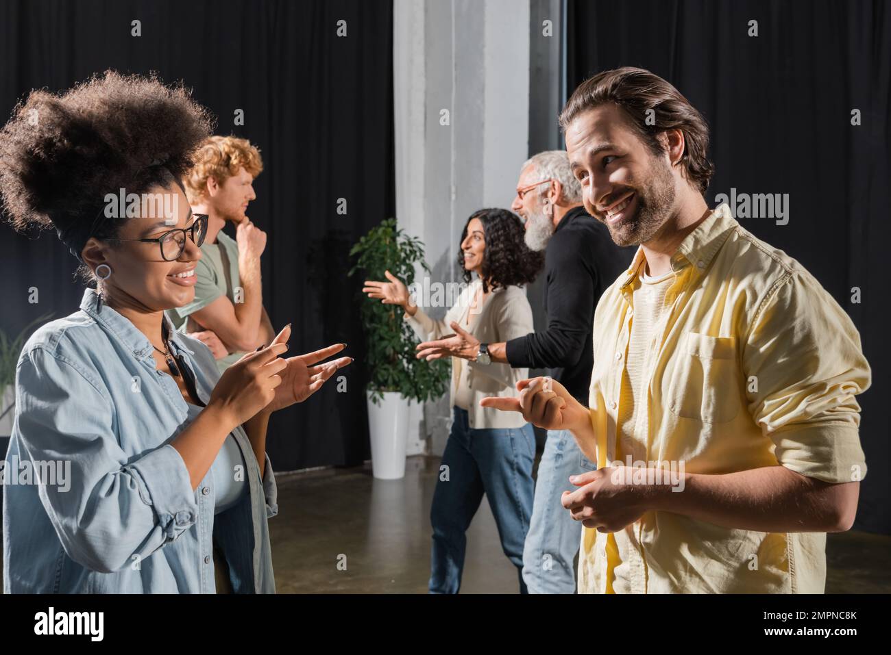 side view of smiling multiethnic students and teacher of acting skills ...