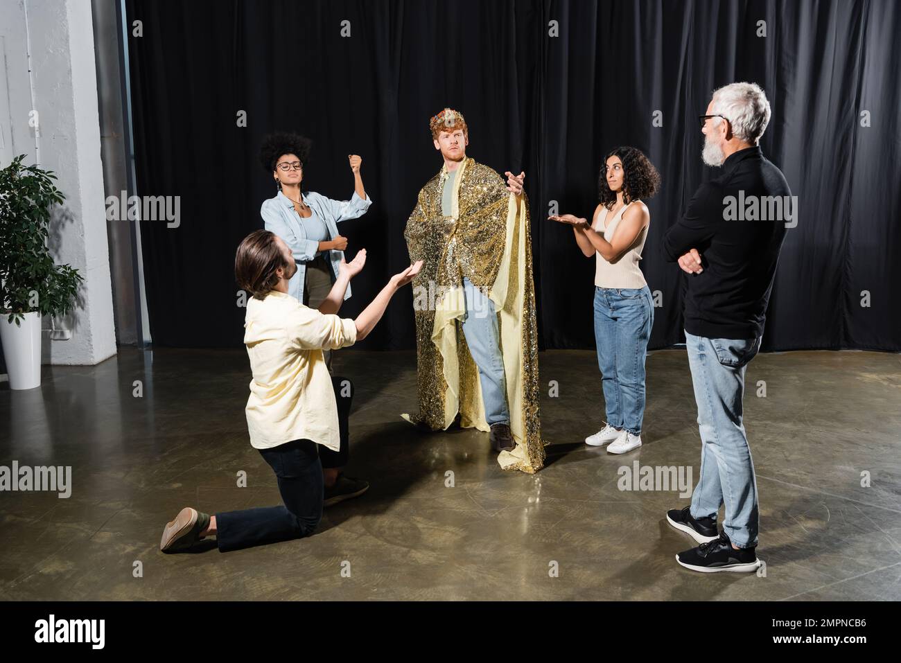 young man in king costume standing with outstretched hand near posing ...