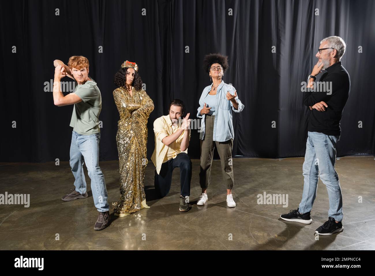 grey haired art director looking at multiracial woman in queen costume ...