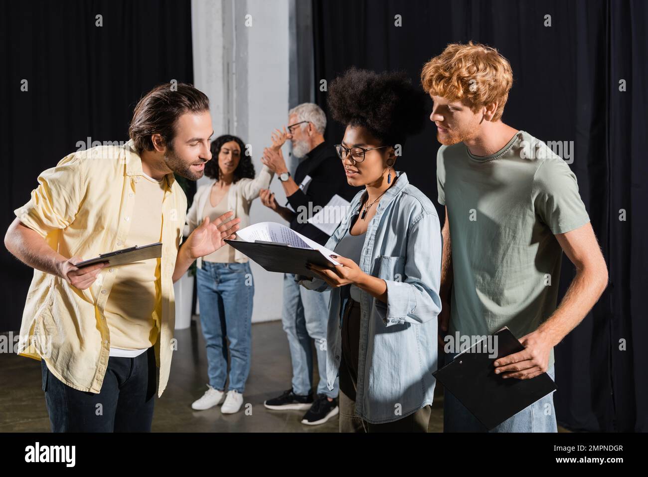 young multicultural actors looking at screenplay during rehearsal in ...