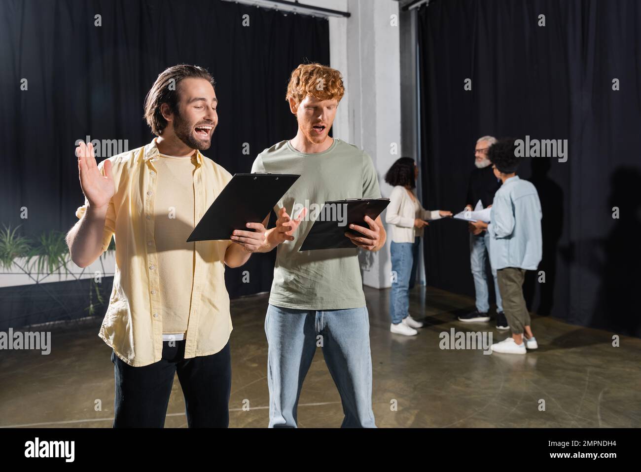 redhead and brunette students holding scenarios and rehearsing in ...