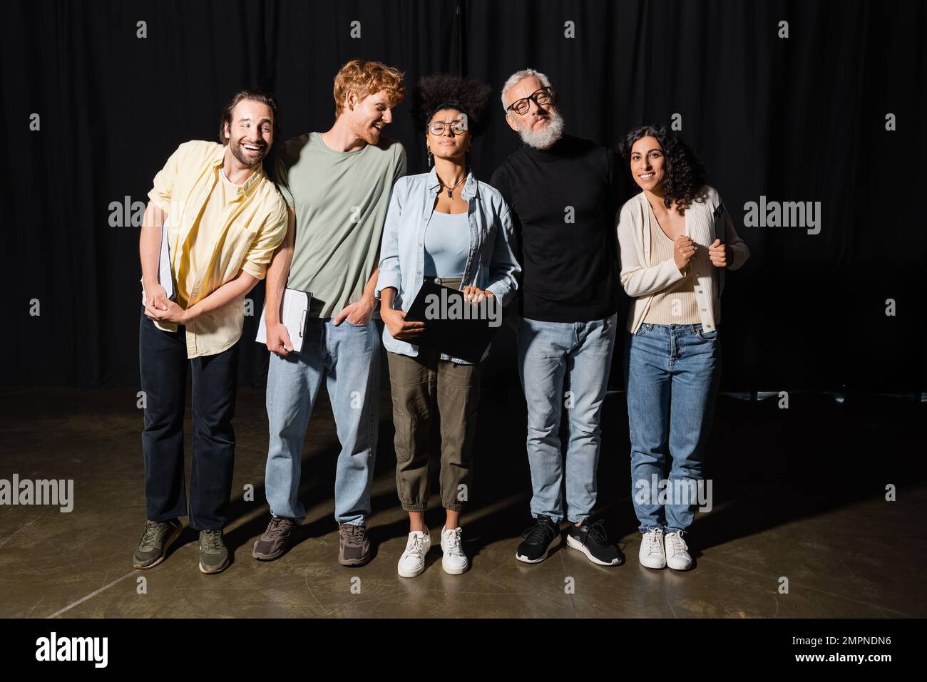 young emotional actors standing on theater stage near grey haired ...