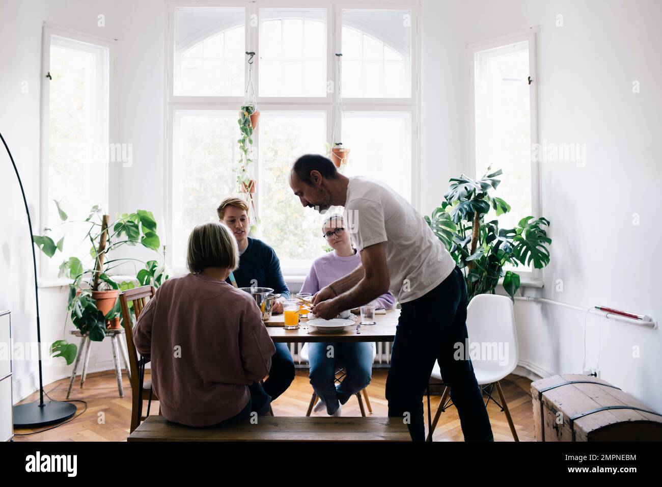 Side view of man serving juice to family on dining table at home Stock ...