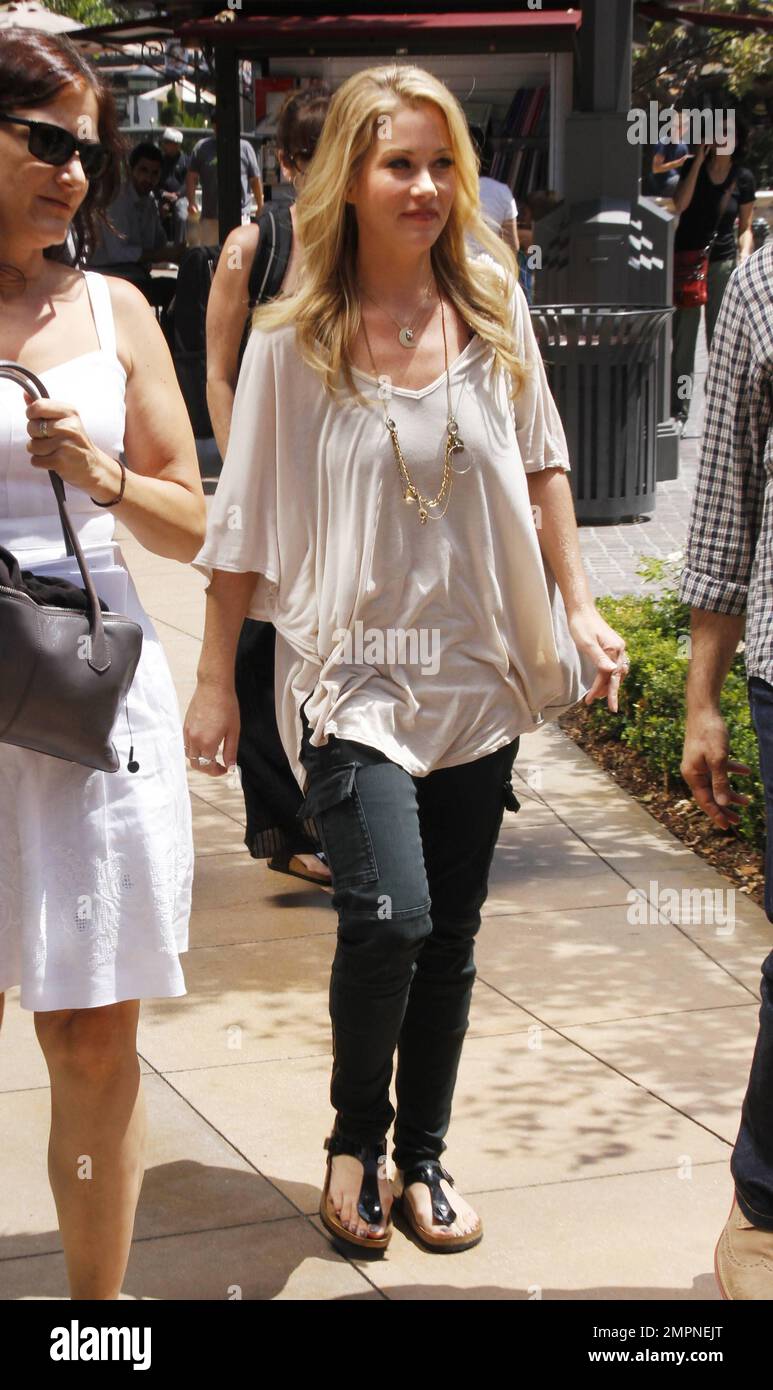 Wearing a loose tan top with black skinny jeans and sandals, Christina ...