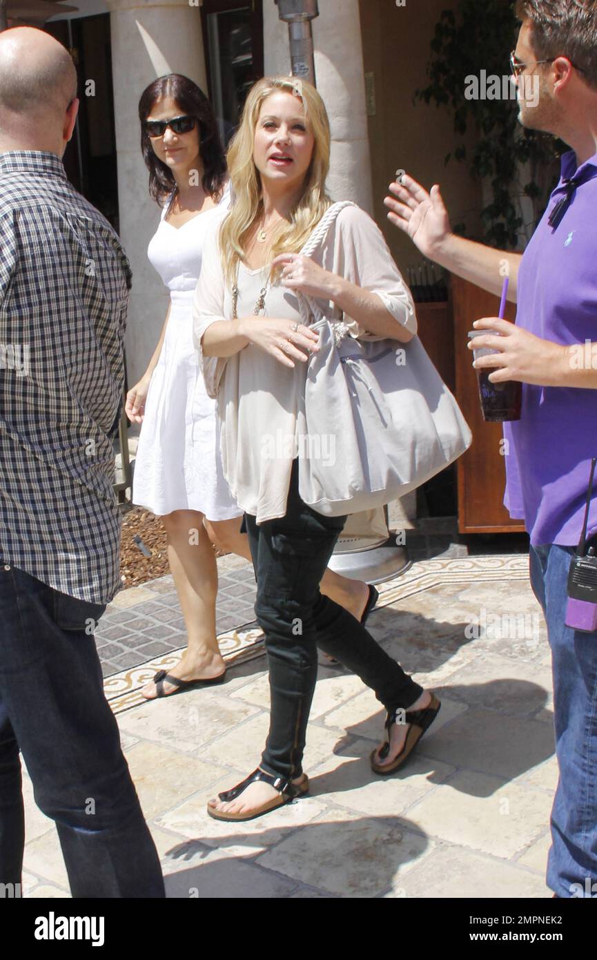 Wearing a loose tan top with black skinny jeans and sandals, Christina ...