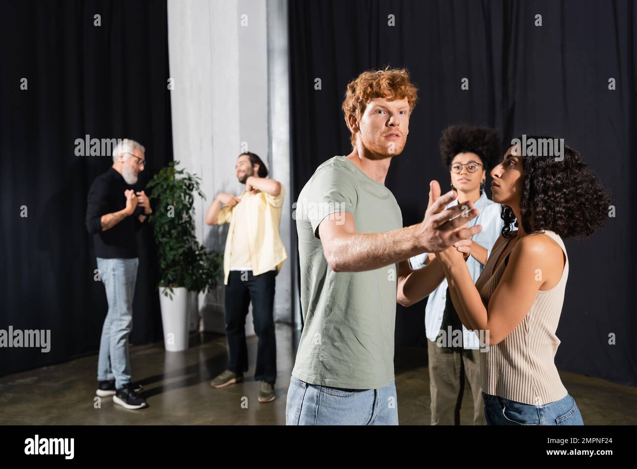 redhead man pointing with hand near interracial actresses and actors on ...