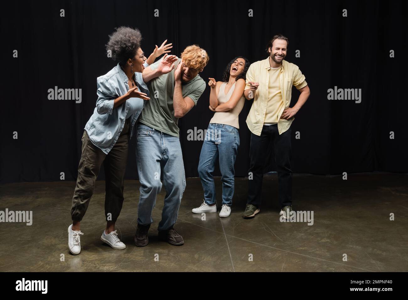 cheerful interracial actors pointing at african american woman ...
