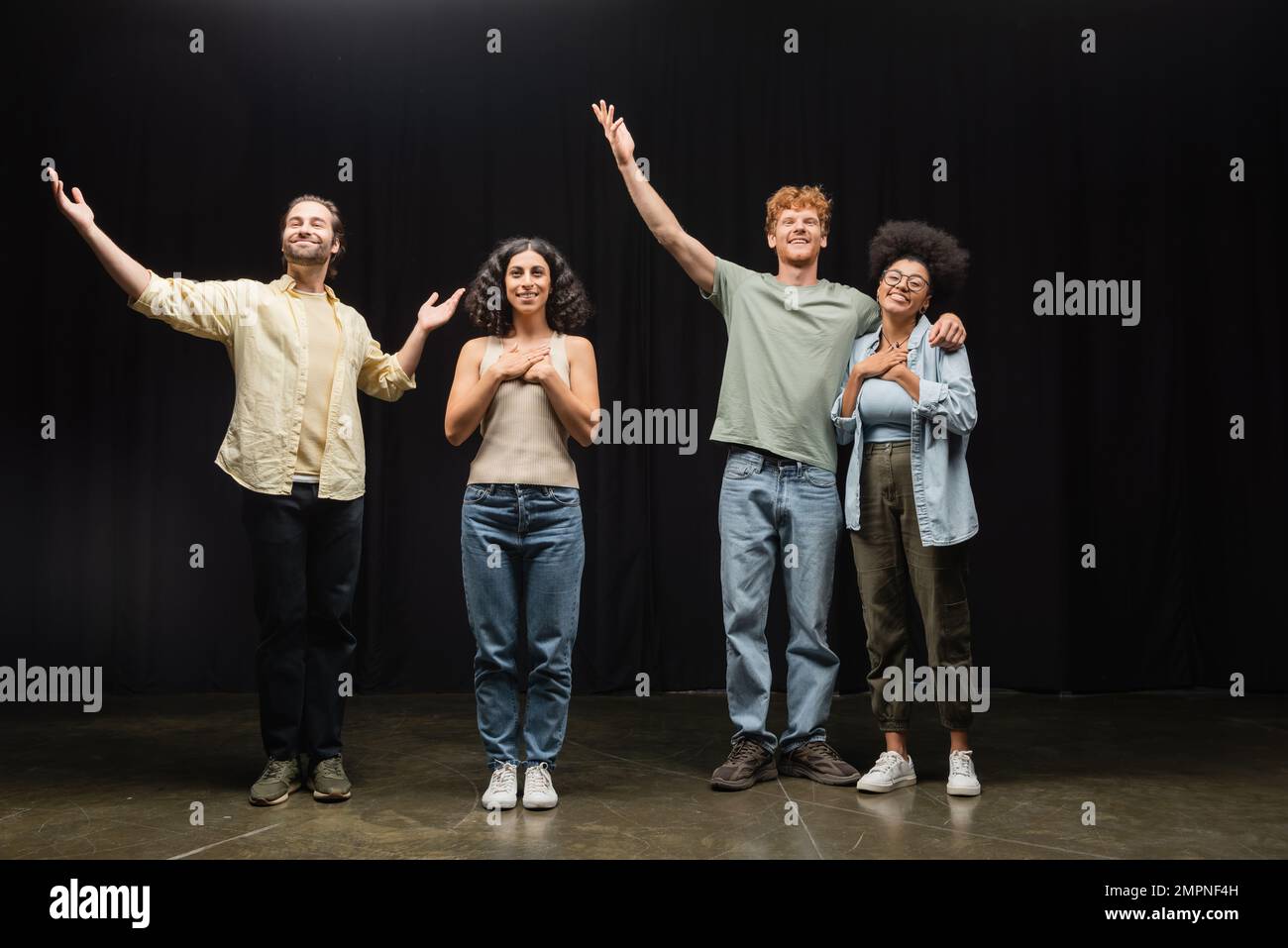 full length of happy multiethnic actors standing with raised hands on ...