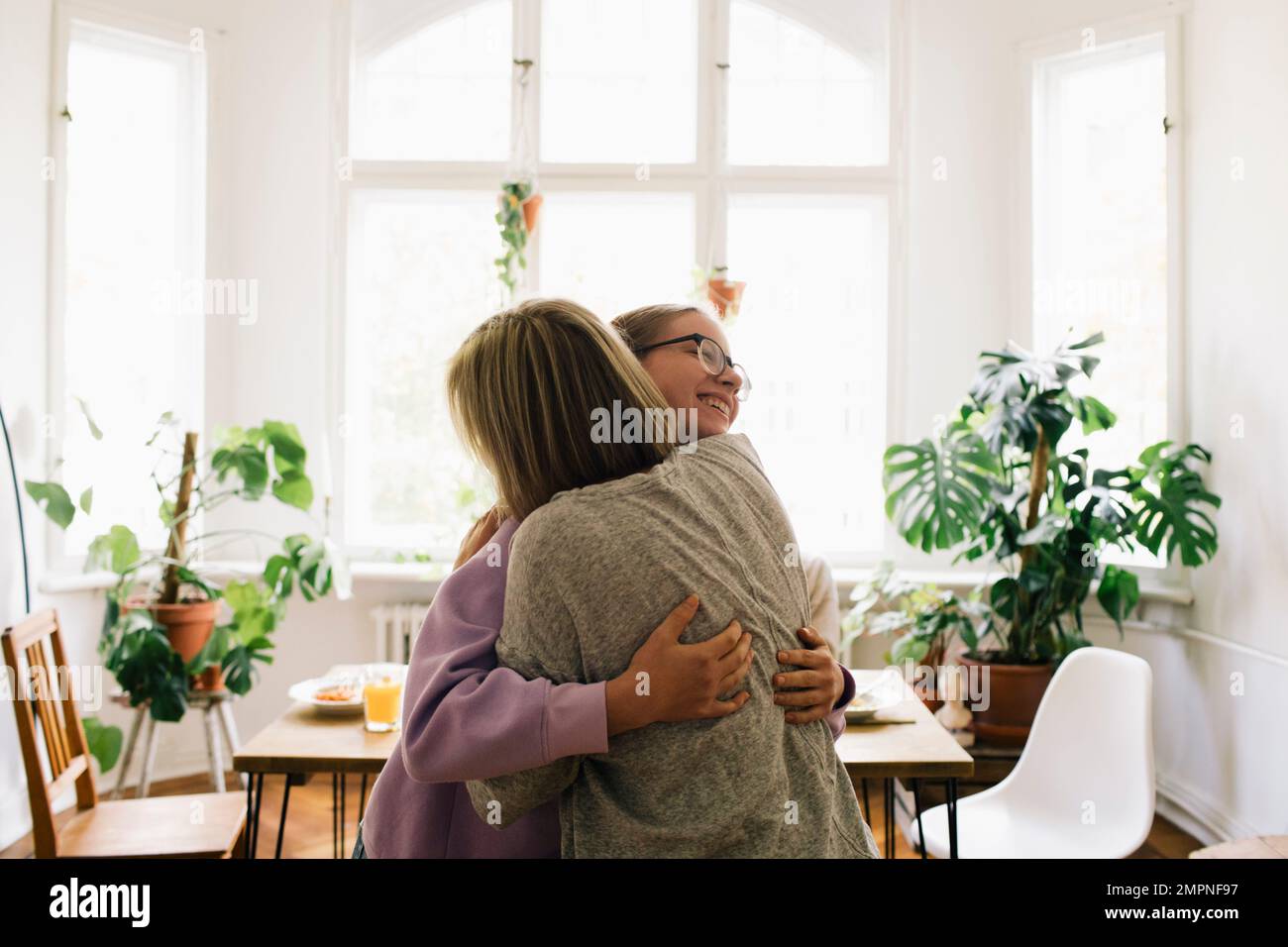 Parent embracing daughter while standing at home Stock Photo - Alamy