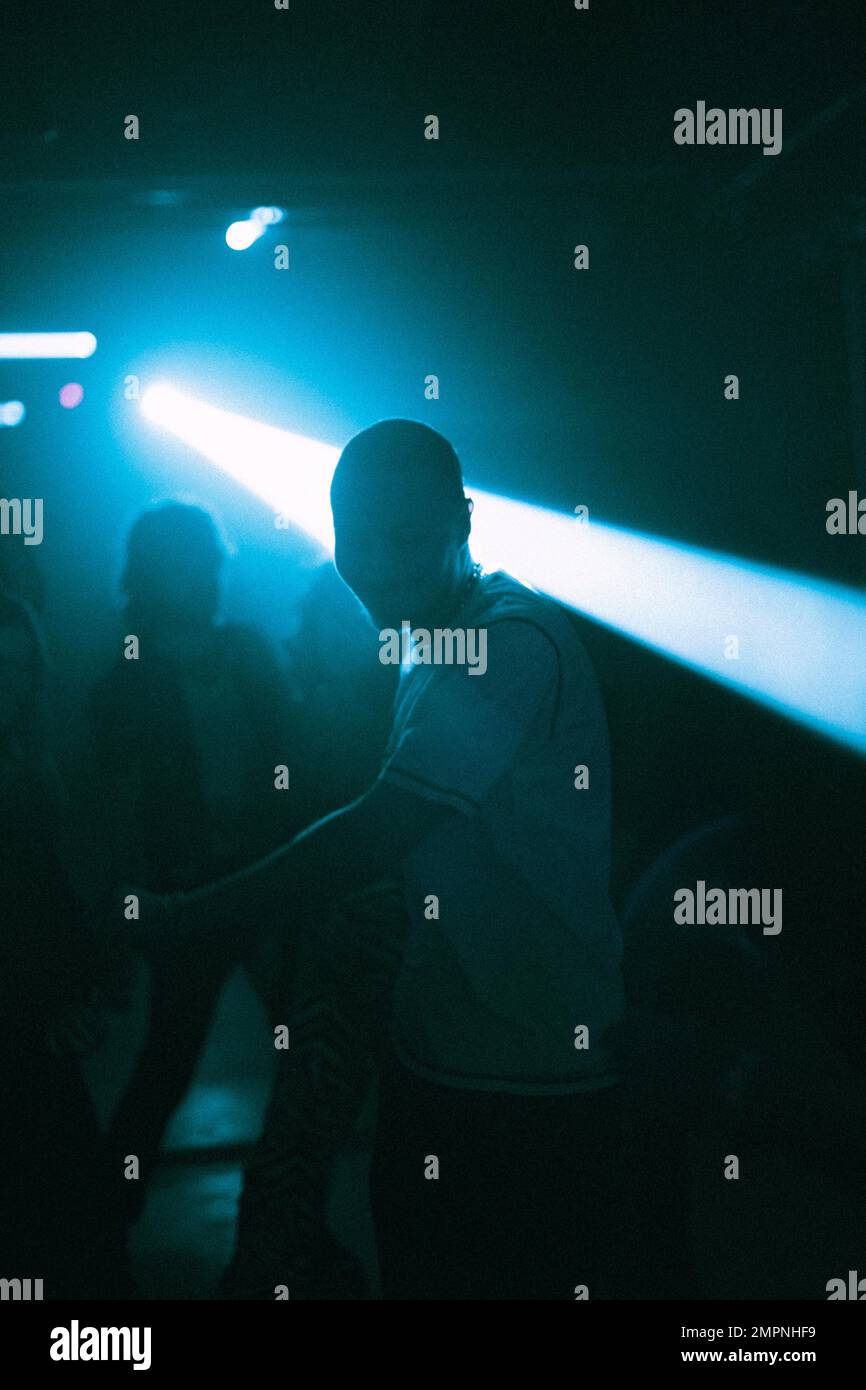 Young man dancing against illuminated spotlight at nightclub Stock ...