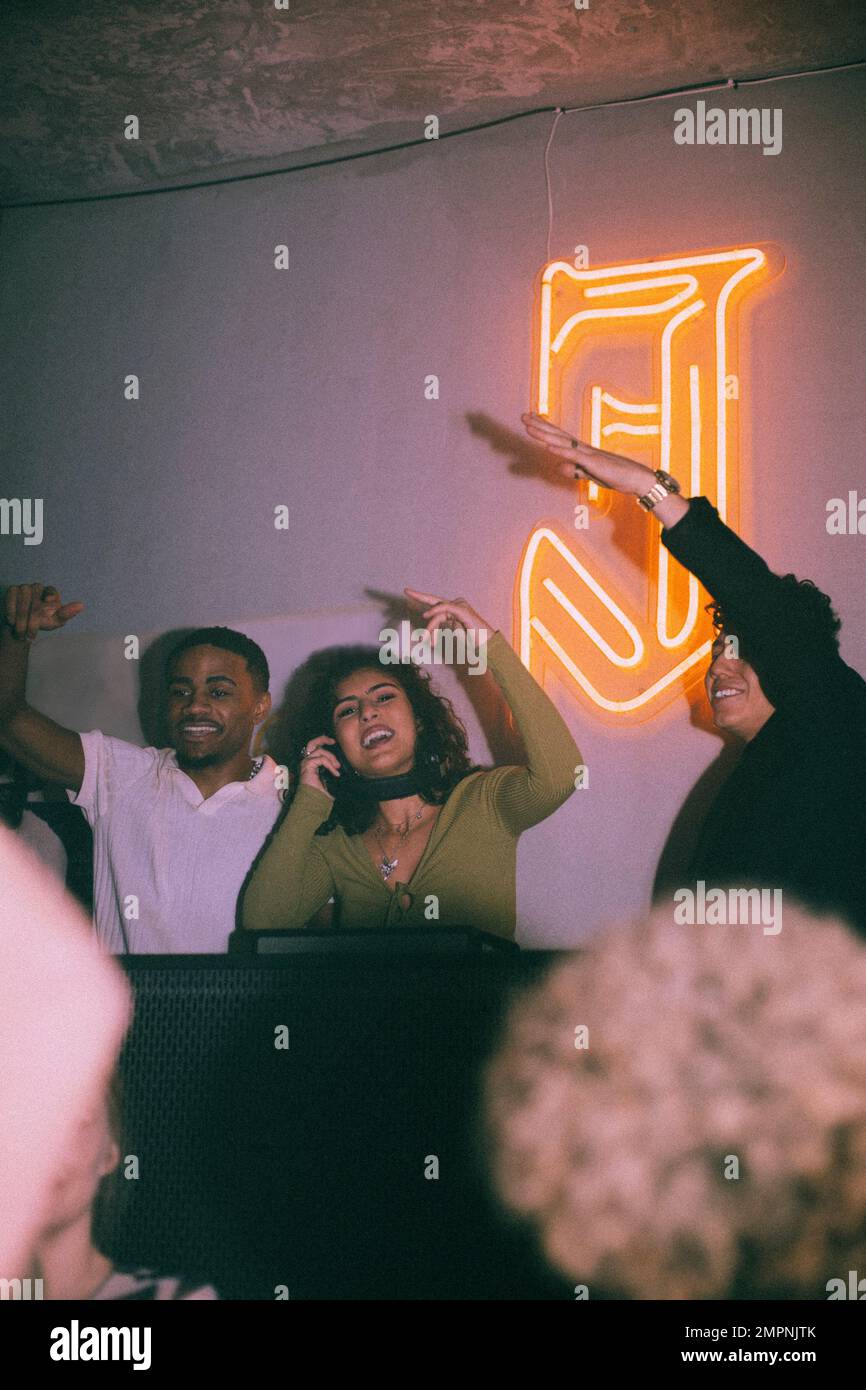 Happy young female DJ amidst friends enjoying at nightclub Stock Photo ...