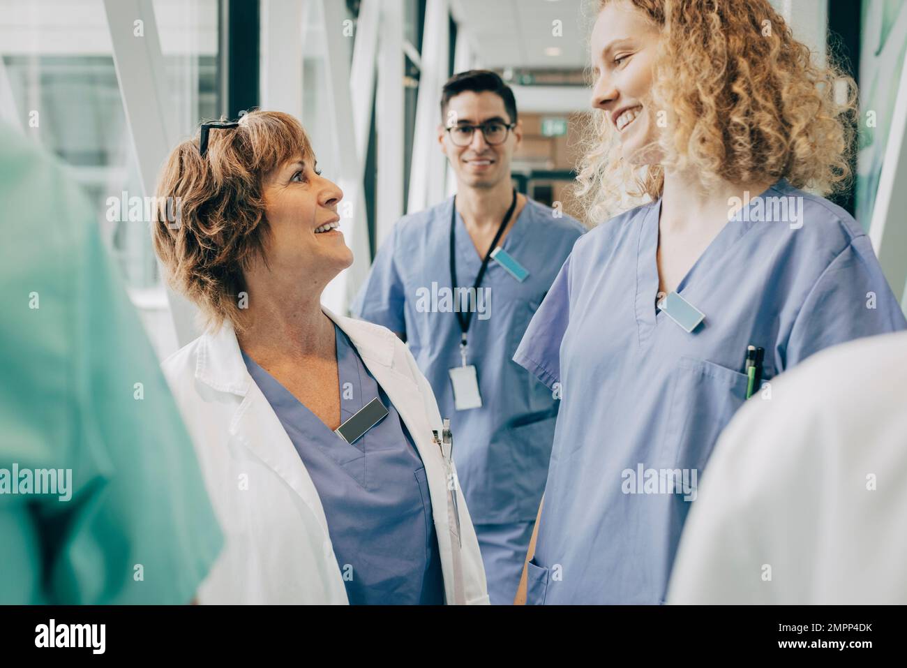 Happy female healthcare workers looking at each other standing in ...