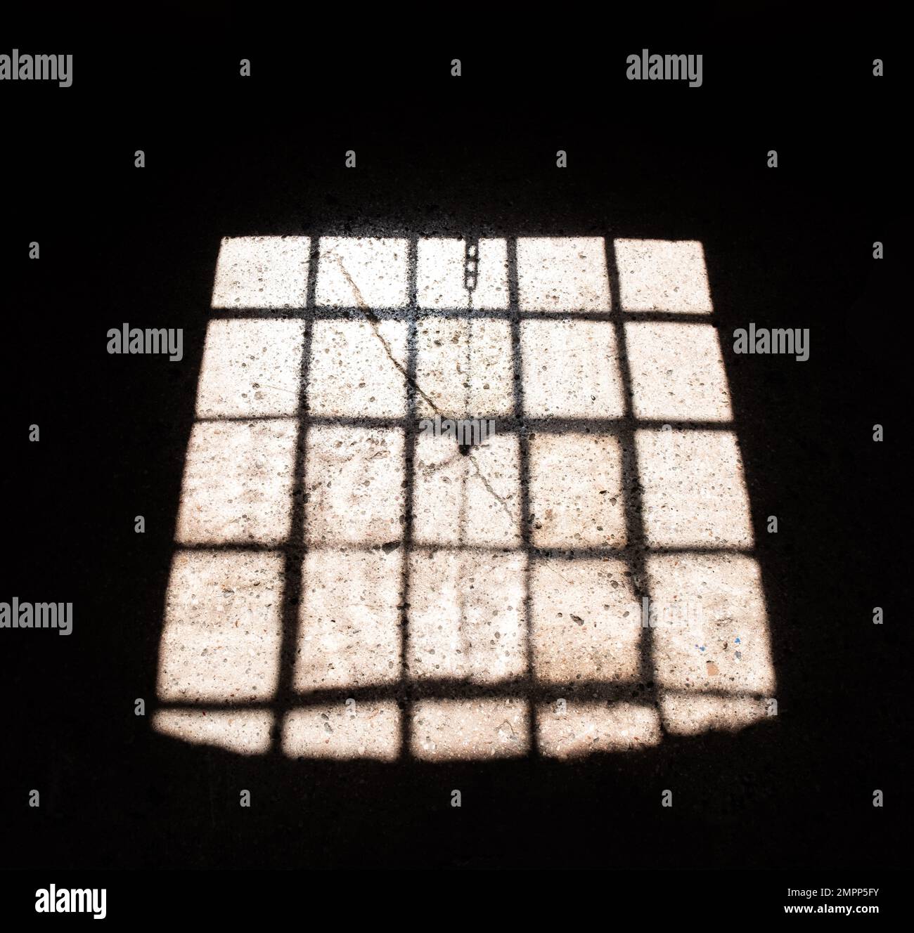 The shadows on the floor of a metal barred window in an abandoned ...