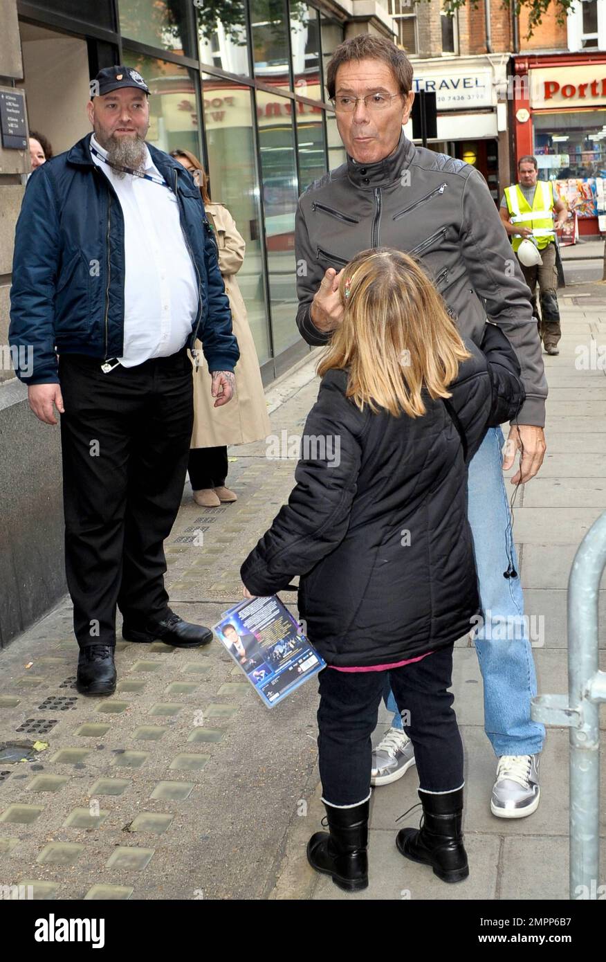 Sir Cliff Richard signs an autograph for a young fan while making an ...
