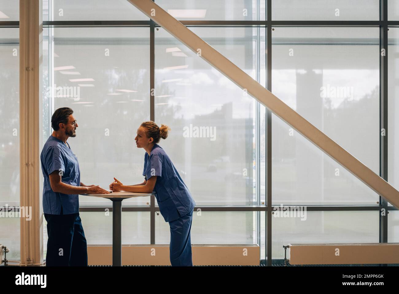 Side view of hospital staff discussing while standing by window in ...