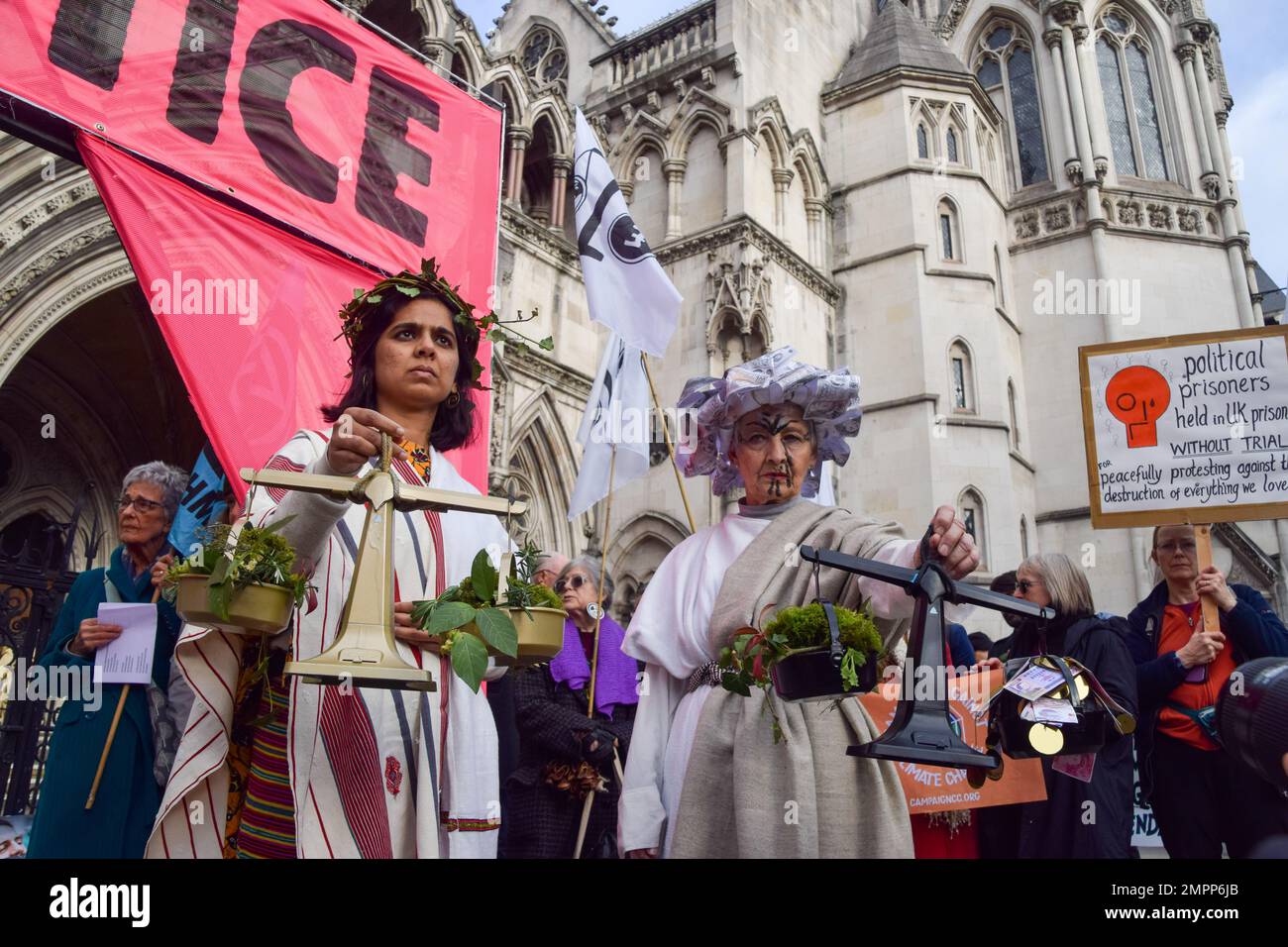 London, UK. 31st January 2023. Activists hold scales, with money ...