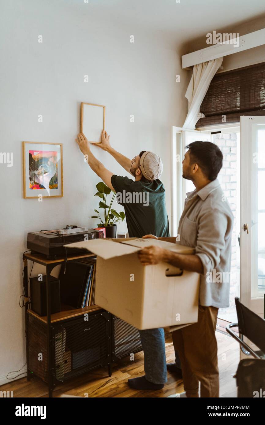 Side view of man with cardboard standing by boyfriend mounting frame on ...