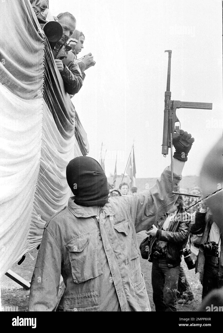 A hooded member of the Provisional IRA waves a submachine gun during ...
