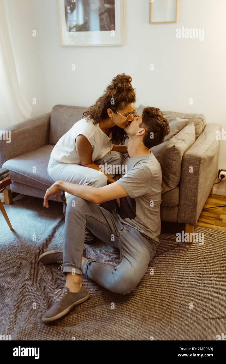 Romantic boyfriend and girlfriend kissing each other sitting in living room at home Stock Photo ...