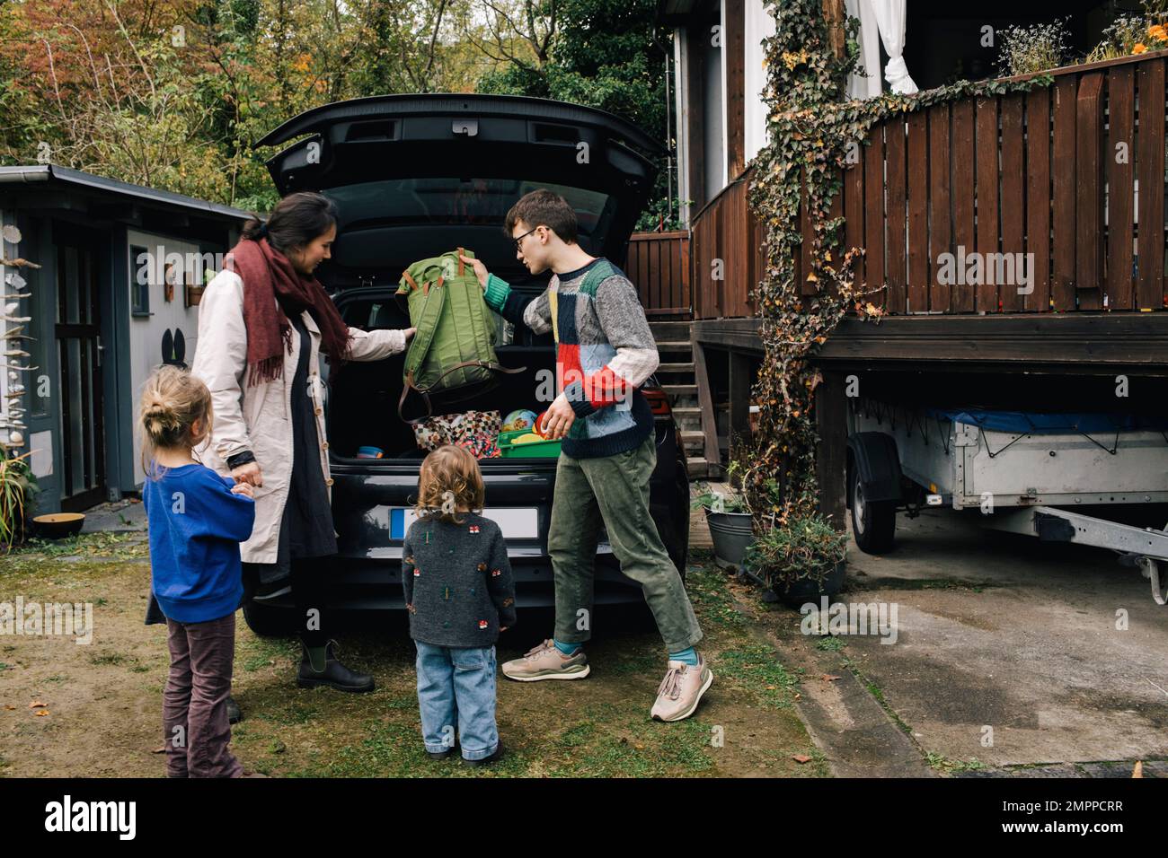 Family preparing for picnic while loading stuff in electric car trunk ...