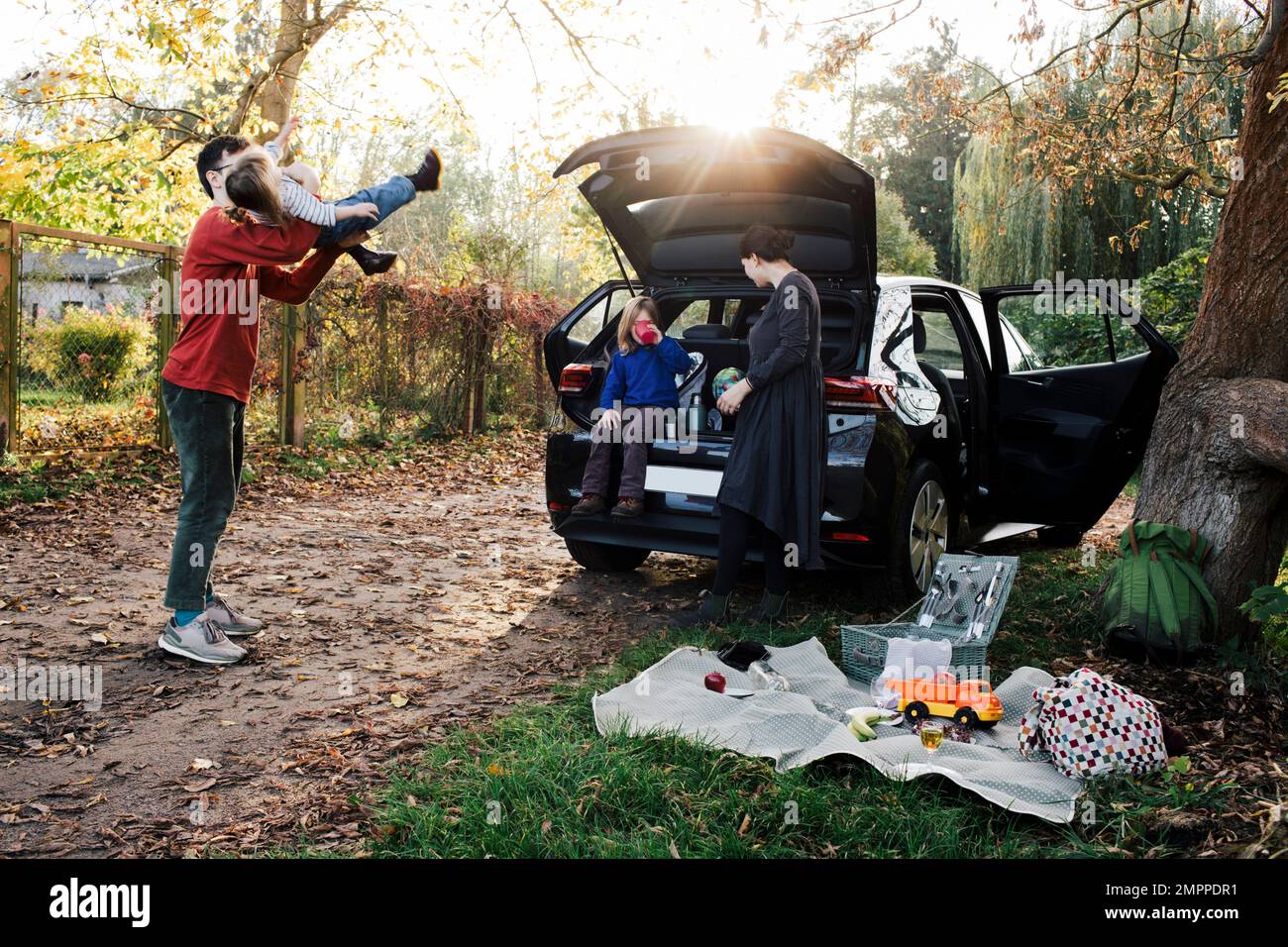 Family enjoying picnic together at yard during sunny day Stock Photo ...