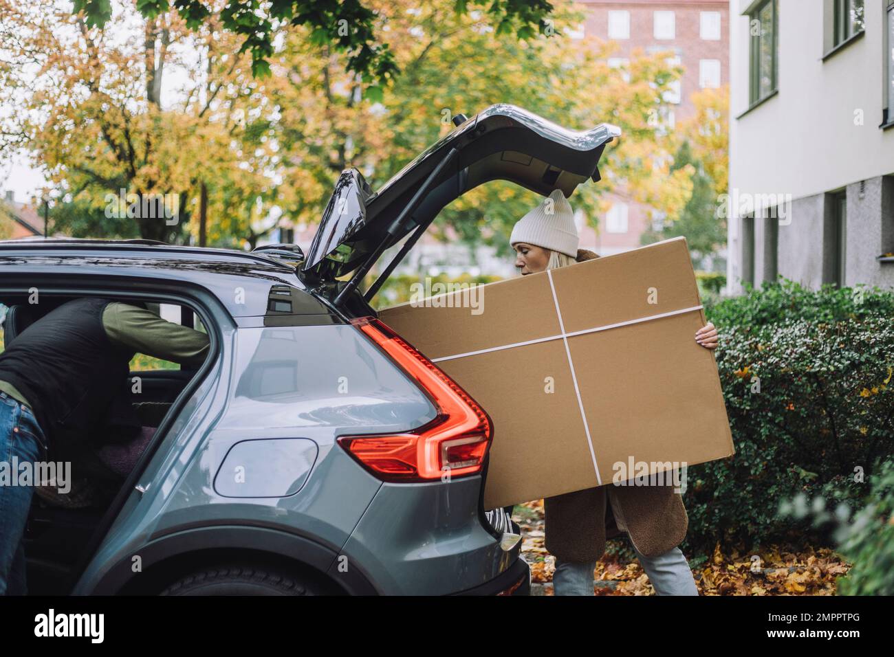 Mature woman loading cardboard in car trunk Stock Photo - Alamy