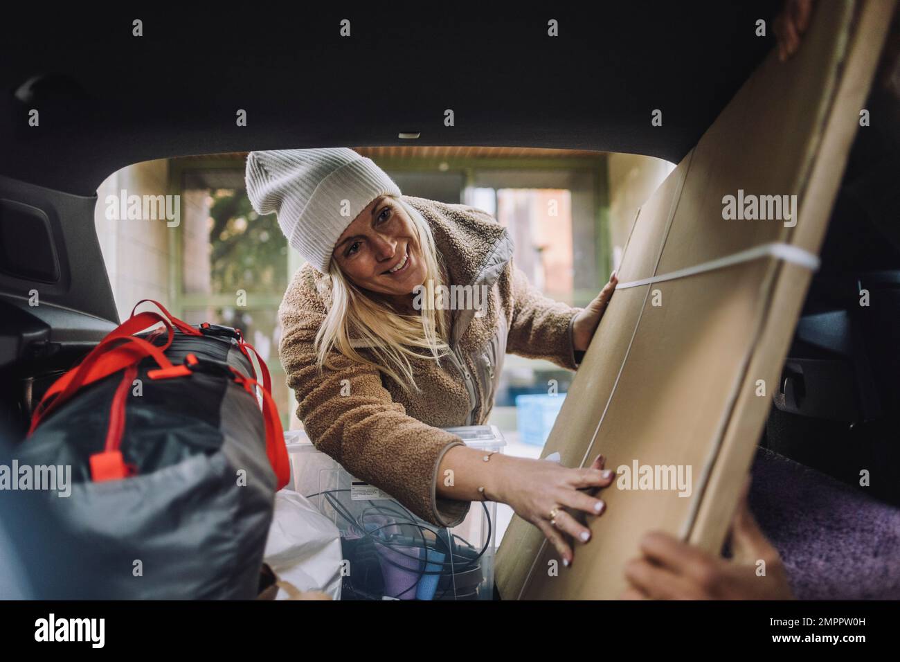 Smiling mature woman loading cardboard in car trunk Stock Photo - Alamy
