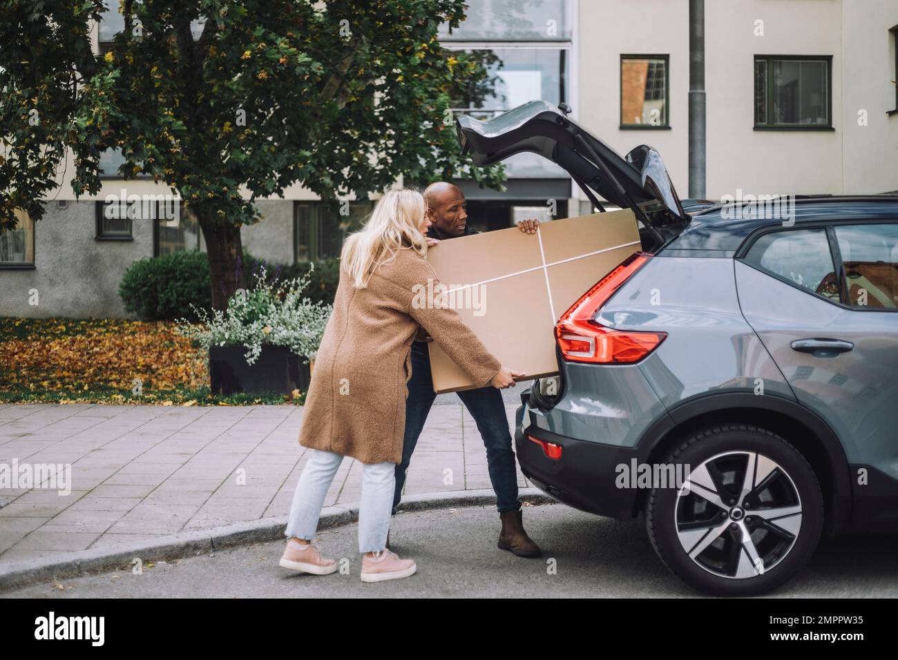 Man and woman loading cardboard together in car trunk Stock Photo - Alamy