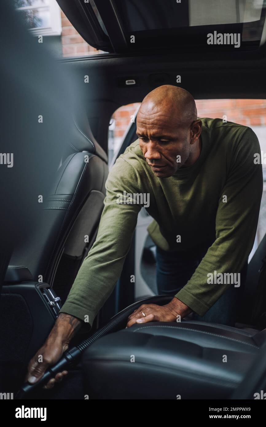 Bald mature man cleaning car with vacuum cleaner Stock Photo - Alamy