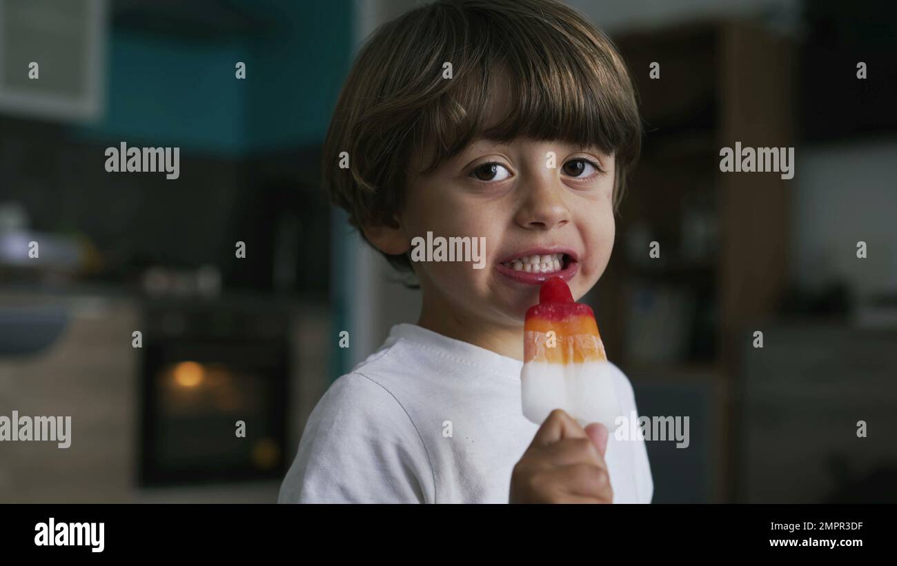 Portrait of a child eating colorful popsicle ice cream. Young boy eats ...