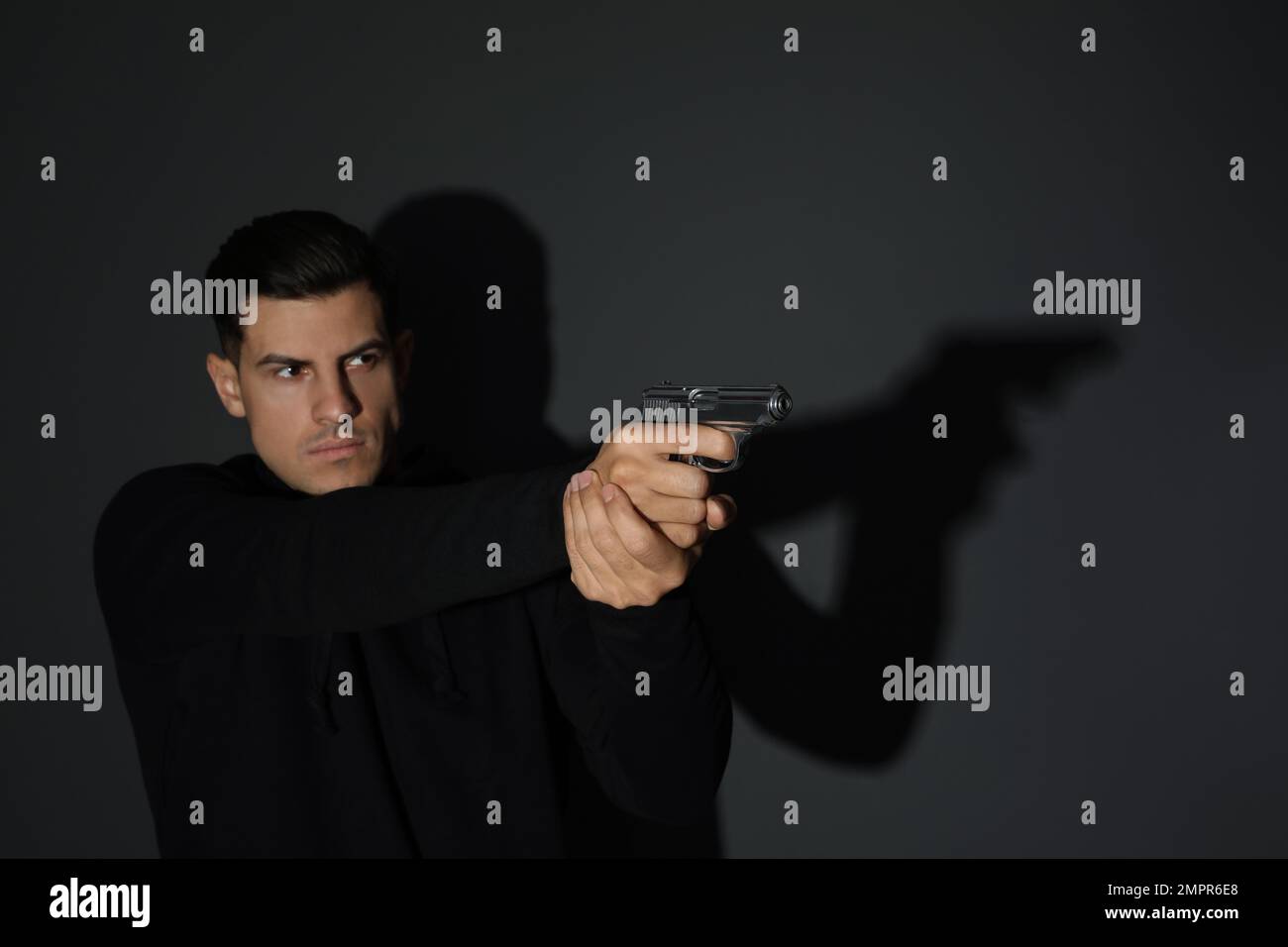 Professional killer with gun on black background Stock Photo - Alamy
