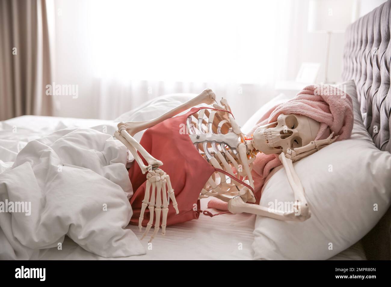 Human skeleton in silk pajamas and towel lying on bed indoors Stock ...