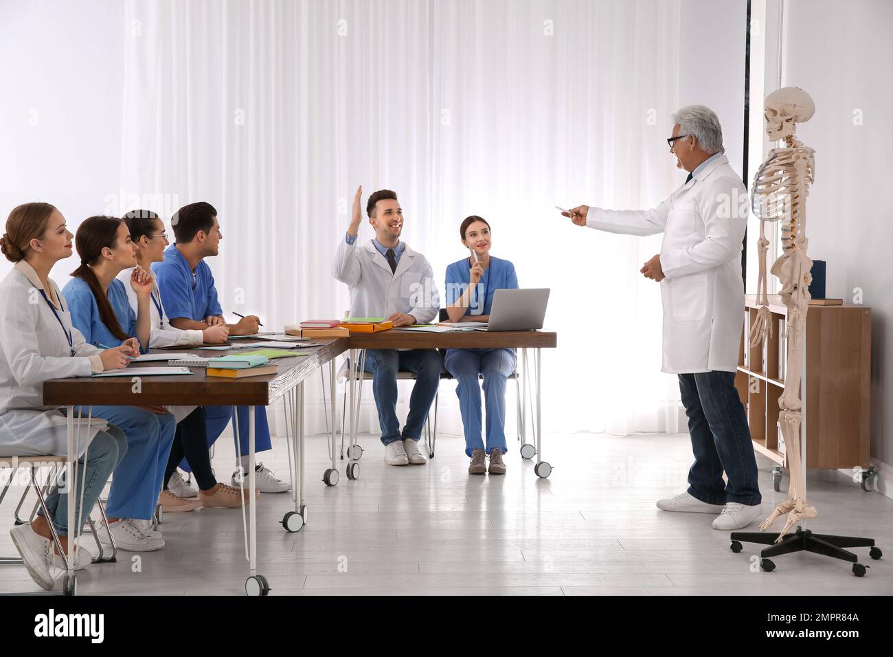 Medical students and professor studying human skeleton anatomy in ...