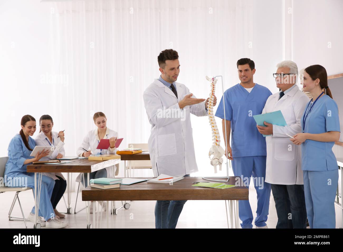 Medical students and professor studying human spine structure in ...