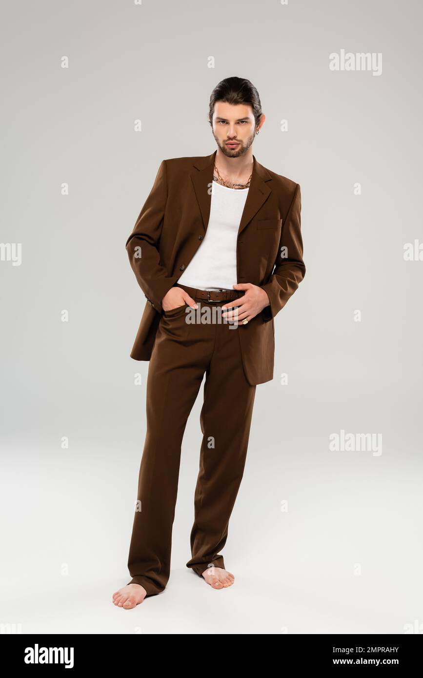 Full length of barefoot man in stylish suit posing on grey background ...